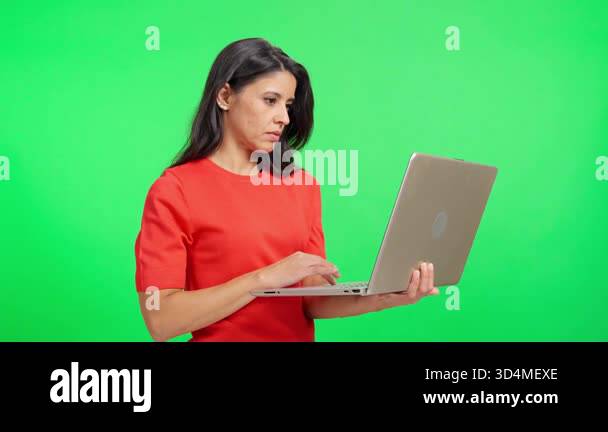 Young woman standing while using a laptop getting shocking news on a ...