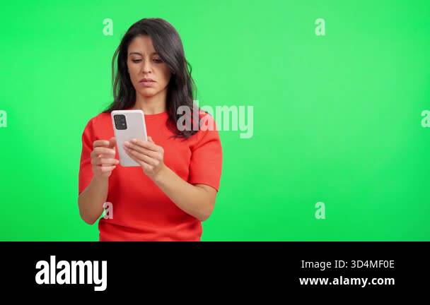 Annoyed woman reading bad news on her mobile phone in front of a green ...