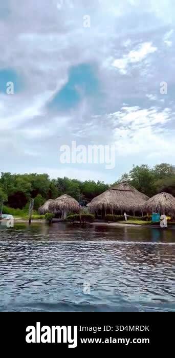 Vertical canoe view of thatched huts, water, beach, and trees in La ...