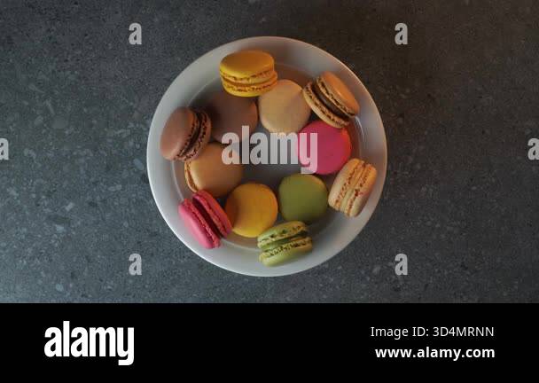 A seamless flatlay loop shows assorted colorful macarons arranged in a ...