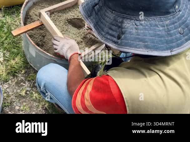 Over-the-shoulder horizontal video of elderly man sifting construction ...
