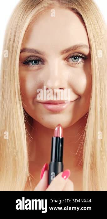 Woman applies lipstick while smiling showcasing a cheerful look and ...