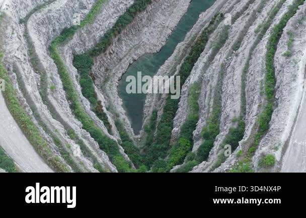 Quarry forming layered spiral grooves around narrow green water channel ...