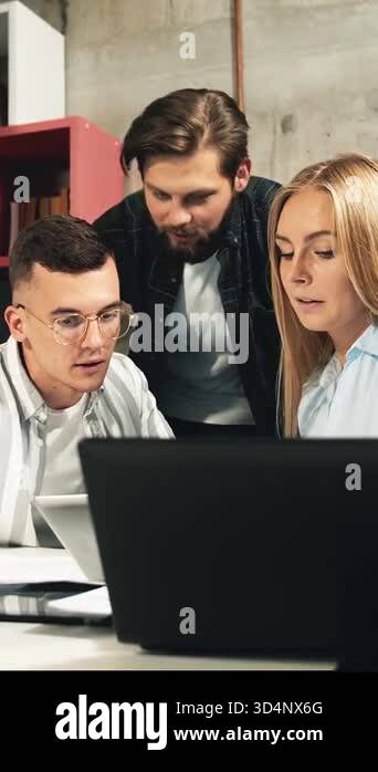 Group of colleagues collaborates on work tasks at their desk in a ...