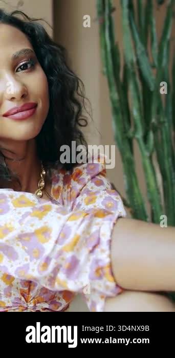 Woman smiles and poses in bright natural light surrounded by greenery ...