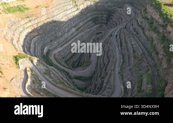 Quarry spiraling inward with terraced levels surrounding deep water ...