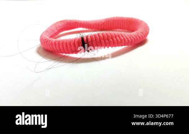 Closeup of a pink hair tie on a white background, with strands of hair ...