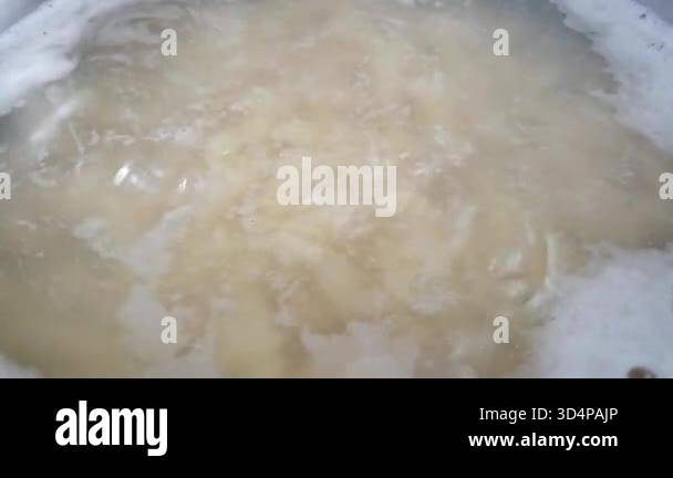 Bubbles form as pasta boils vigorously in a pot of water. the frothy ...
