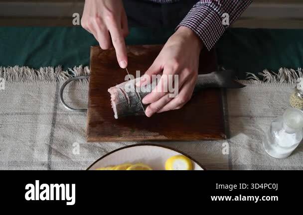 A man makes incisions in a gutted sea bass fish Stock Video Footage - Alamy