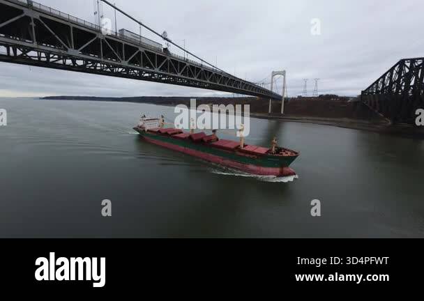 dynamic aerial view of a red cargo vessel turning near twin bridges ...
