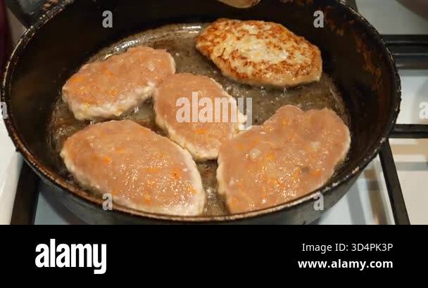 Meat cutlets are fried in a frying pan. A cook turns the cutlets over ...
