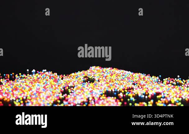Vibrant sprinkles cascade onto a black surface Stock Video Footage - Alamy