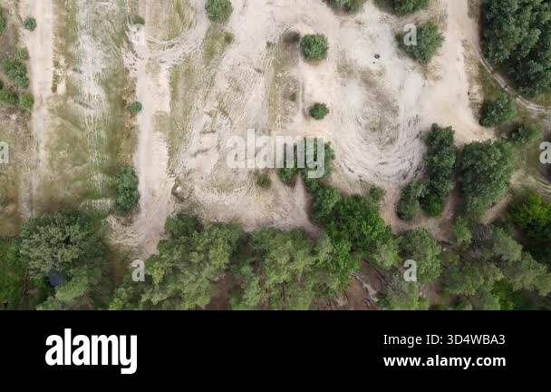 Top-down drone shot flying above sandy paths and trees, moving smoothly ...