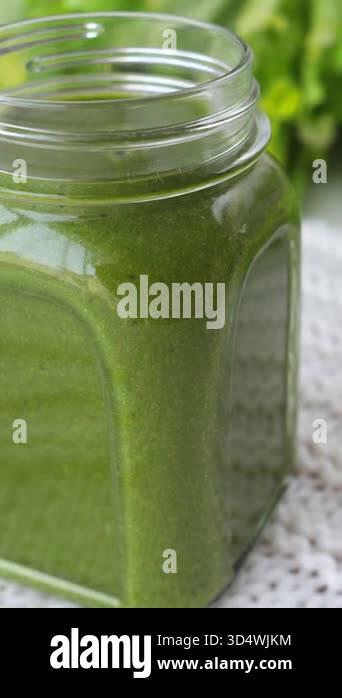 Freshly made green detox smoothie slowly rotating in a glass mason jar ...
