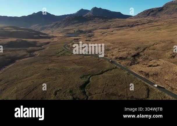 Aerial view of cars on a countryside road through an ample desolate ...