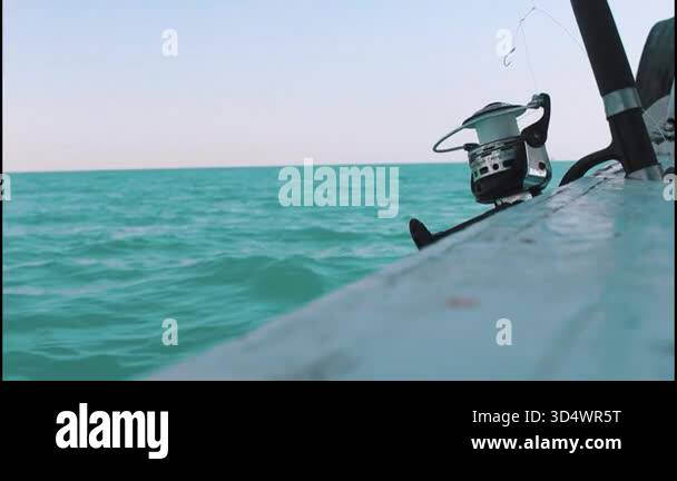 A close up shot of a fishing reel attached to a rod on the side of a ...