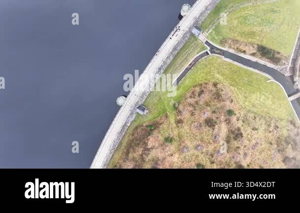 concrete path beside tranquil lake, engineers examine dam curve above ...