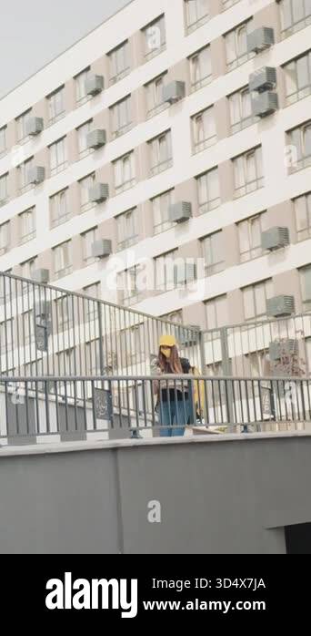 A woman wearing a yellow cap and face mask is holding food packages ...