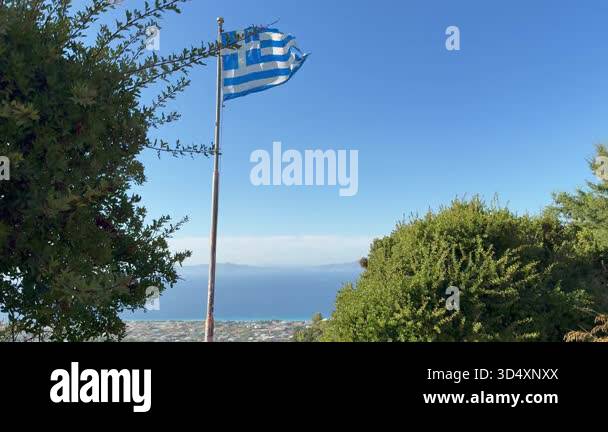 The Greek flag waves in the wind on a bright sunny day overlooking the ...
