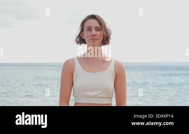 Young woman with short hair in prayer pose with hands together smiling ...