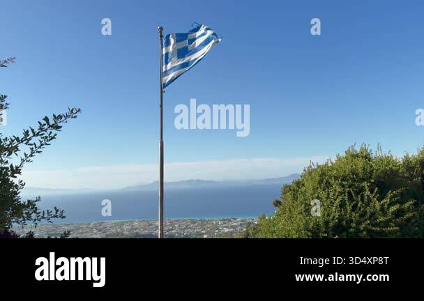 The national flag of Greece is blowing gently in the breeze. A distant ...