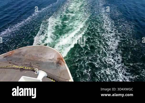Wake of cruise ship. Boat creates foam on sea surface. Back view of ...