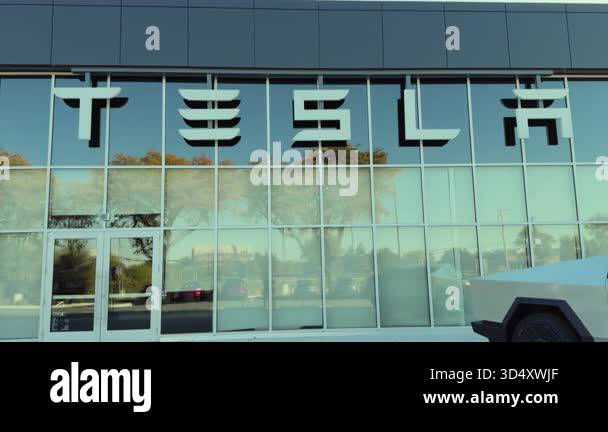 Exterior sign of Tesla dealership. Cyber truck is parked at entrance of ...