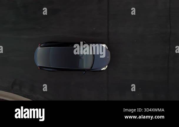 Above view of Tesla driving through an empty suburban black parking lot ...