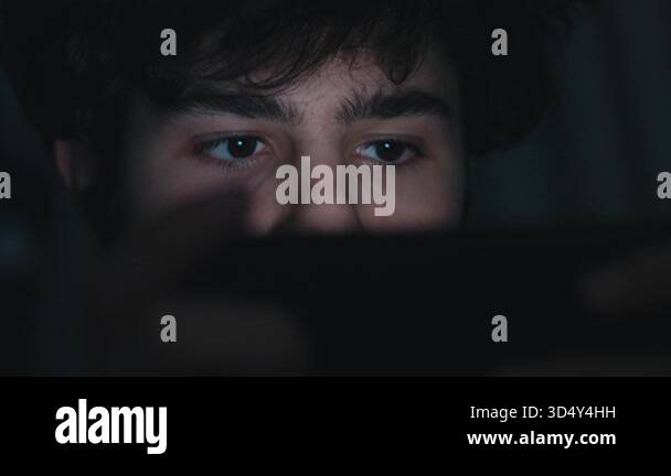 Gazing intently at screen amidst dim lighting, Maintaining deep eye ...