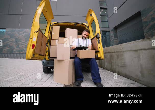 Delivery service employee in uniform sitting in the back of a yellow ...