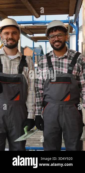 Portrait of two happy multicultural construction workers in hard hats ...