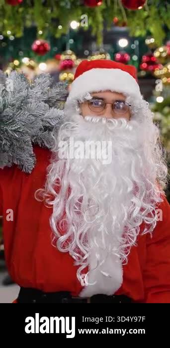 Happy santa claus with glasses and a long white beard carrying a snow ...