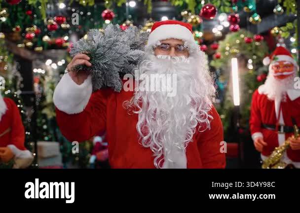 Joyful santa claus with a long white beard and glasses carrying a snow ...