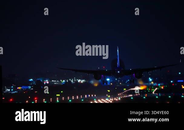 Commercial aircraft approaching runway for landing at night with city ...
