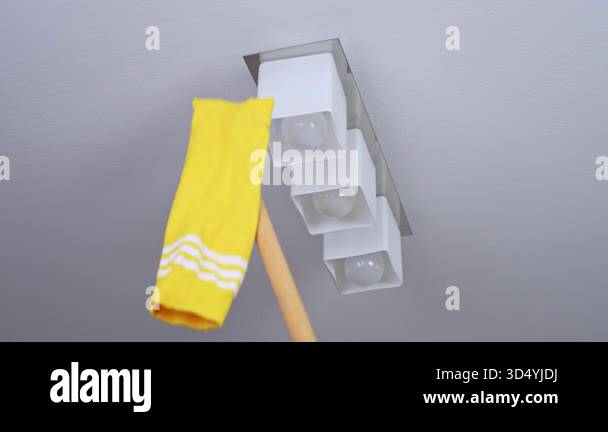 person throws a yellow sock onto a light bulb with a long stick during ...