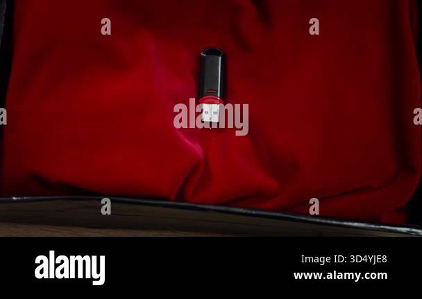 A USB drive lying on an expensive red cloth is captured in slow motion ...