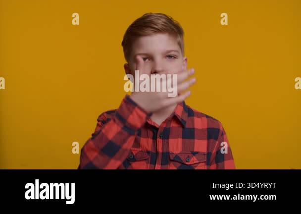 A young boy covers his face with his hand in a classic facepalm gesture ...
