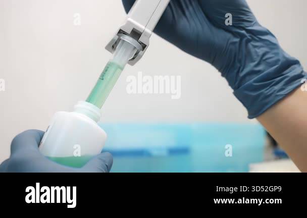 Close up of scientist hands in gloves pipetting reagent solution into ...