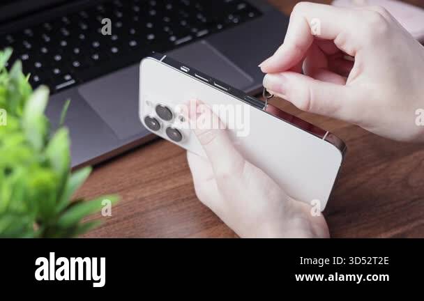 Close-up view of person installing a SIM card into a white mobile phone ...