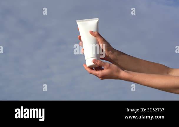 Female hands holding white mockup tube of lotion cream and squeezing it ...