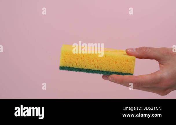 Close-up of female hands pouring dishwashing gel onto yellow sudsy ...