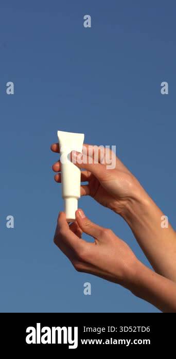 Vertical video of female hand holding white mockup tube of serum that ...