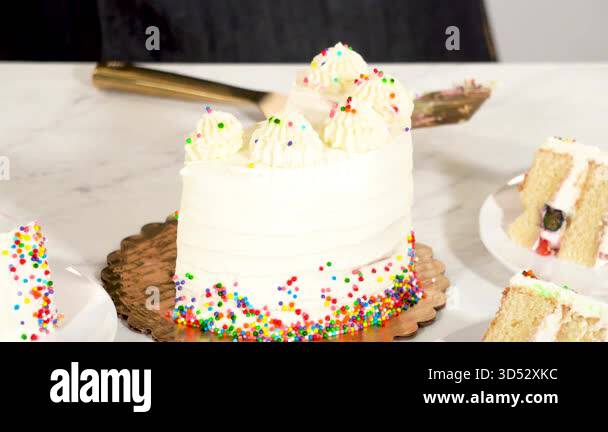 A person cuts and lifts a slice of a small round birthday cake with ...