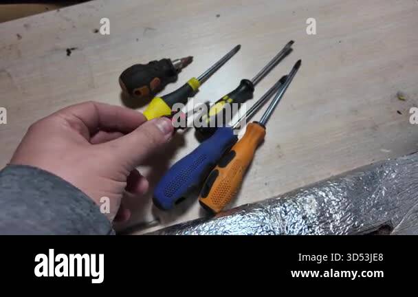 screwdriver in hands. Close-up of black male hand fixing self tapping ...