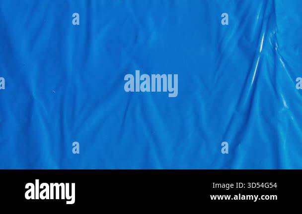 Bright blue plastic wrap sheet surface with creases and folds ...