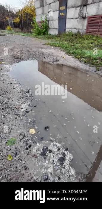Puddles on the road, slow motion. Autumn raindrops fall into a large ...