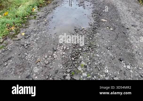 Puddles on the road, slow motion. Autumn raindrops fall into a large ...