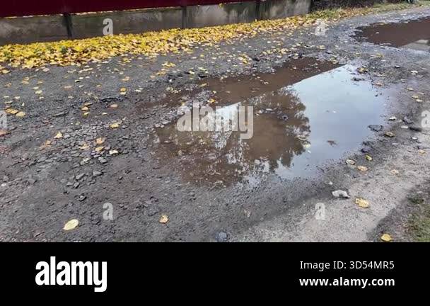 Puddles on the road, slow motion. Autumn raindrops fall into a large ...