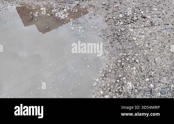 Puddles on the road, slow motion. Autumn raindrops fall into a large ...