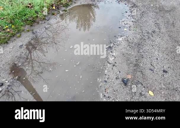Puddles on the road, slow motion. Autumn raindrops fall into a large ...